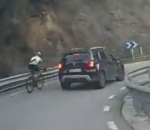 Un cycliste essaie de doubler une voiture sur une route sinueuse ...